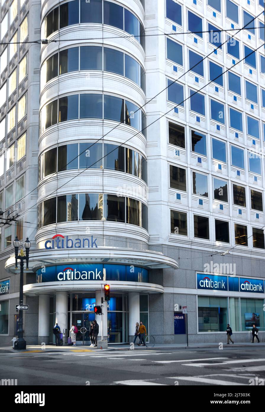 Banking customers, including a couple with suitcases, wait outside for ...