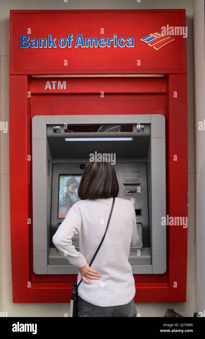 A woman makes a cash withdrawal from a Bank of America ATM machine in ...
