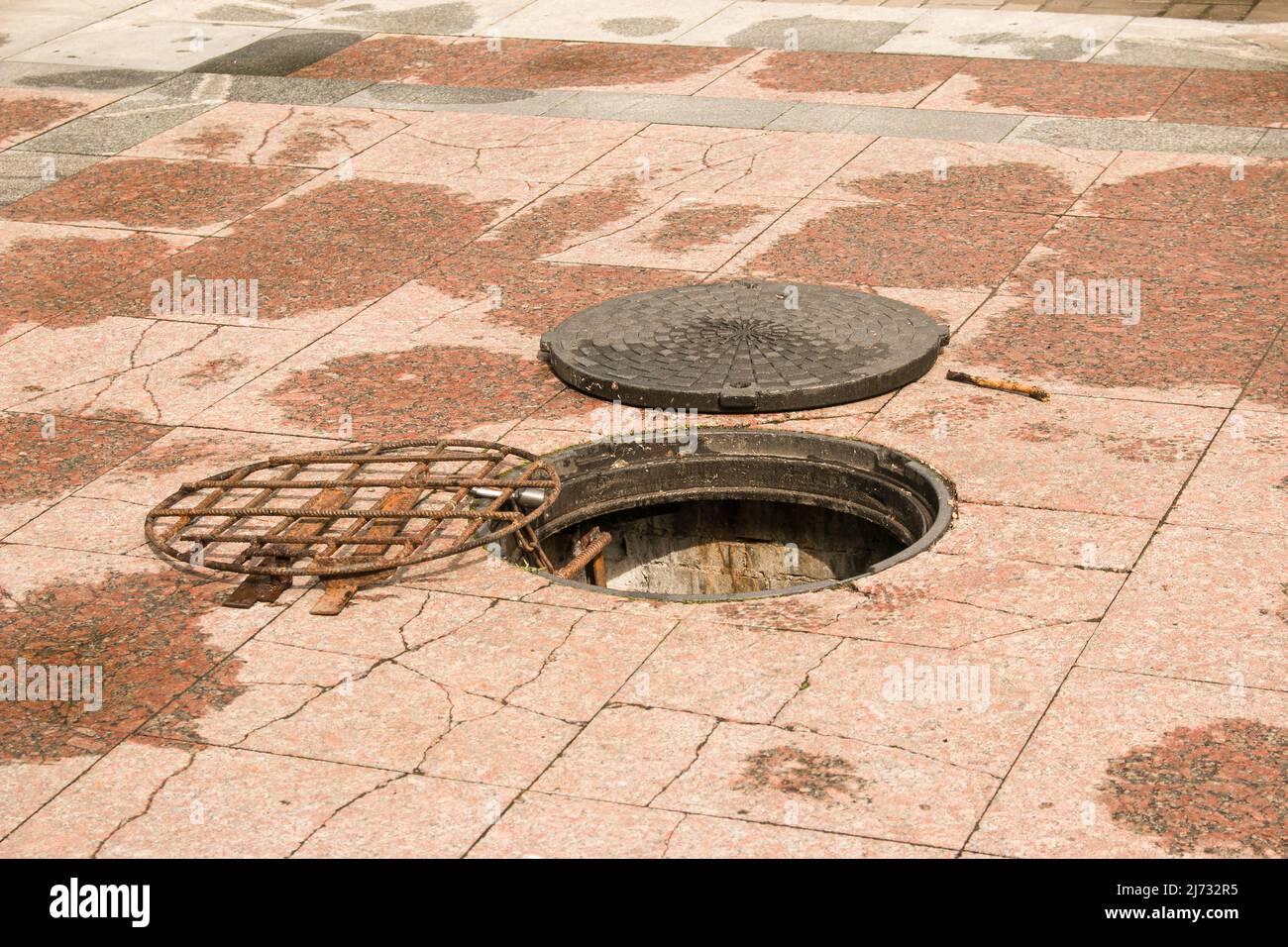 An open manhole on the road. Dangerous open unsecured hatch on the road ...
