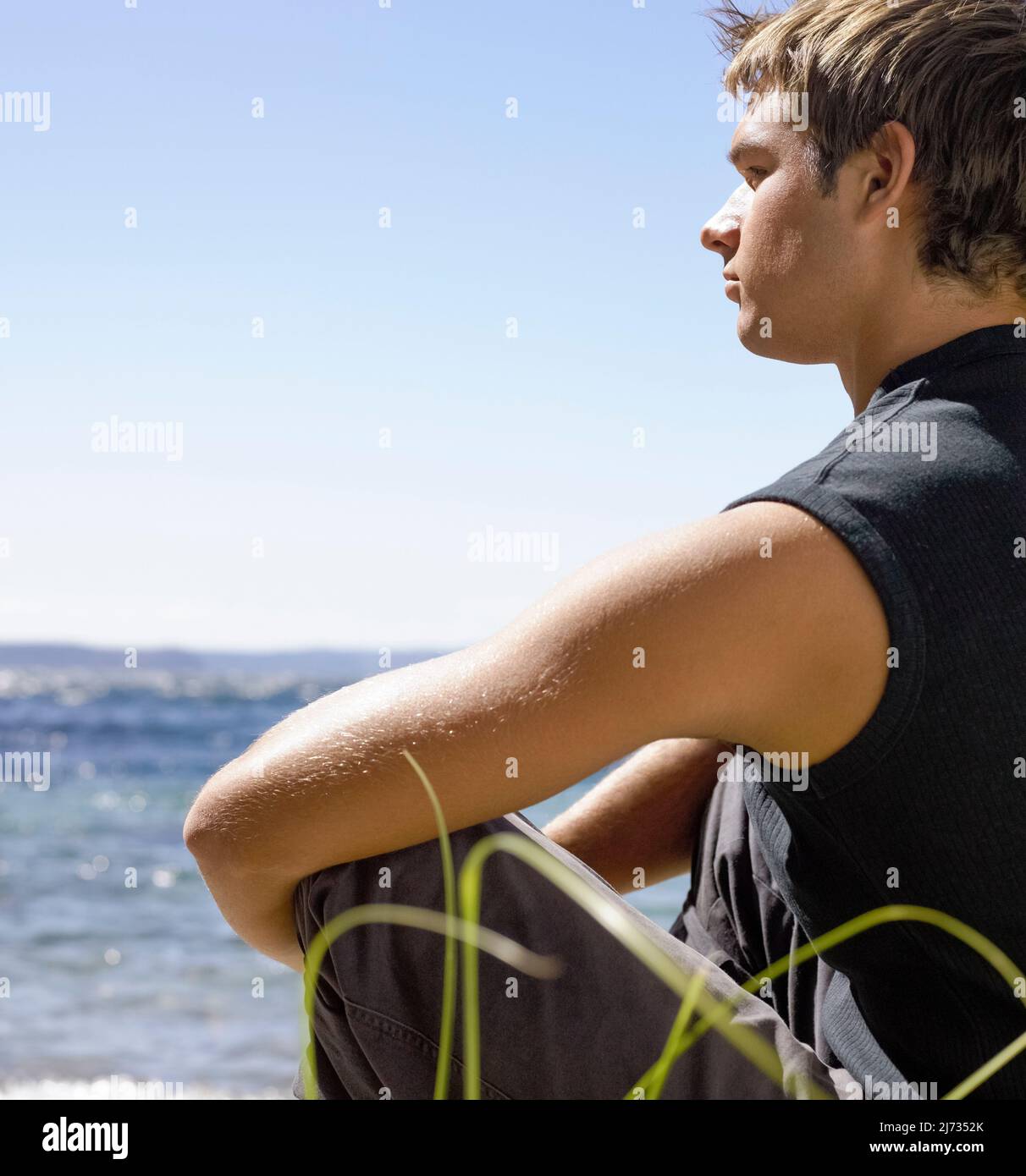 Young man sitting on the bank relaxing at the lake edge Stock Photo - Alamy