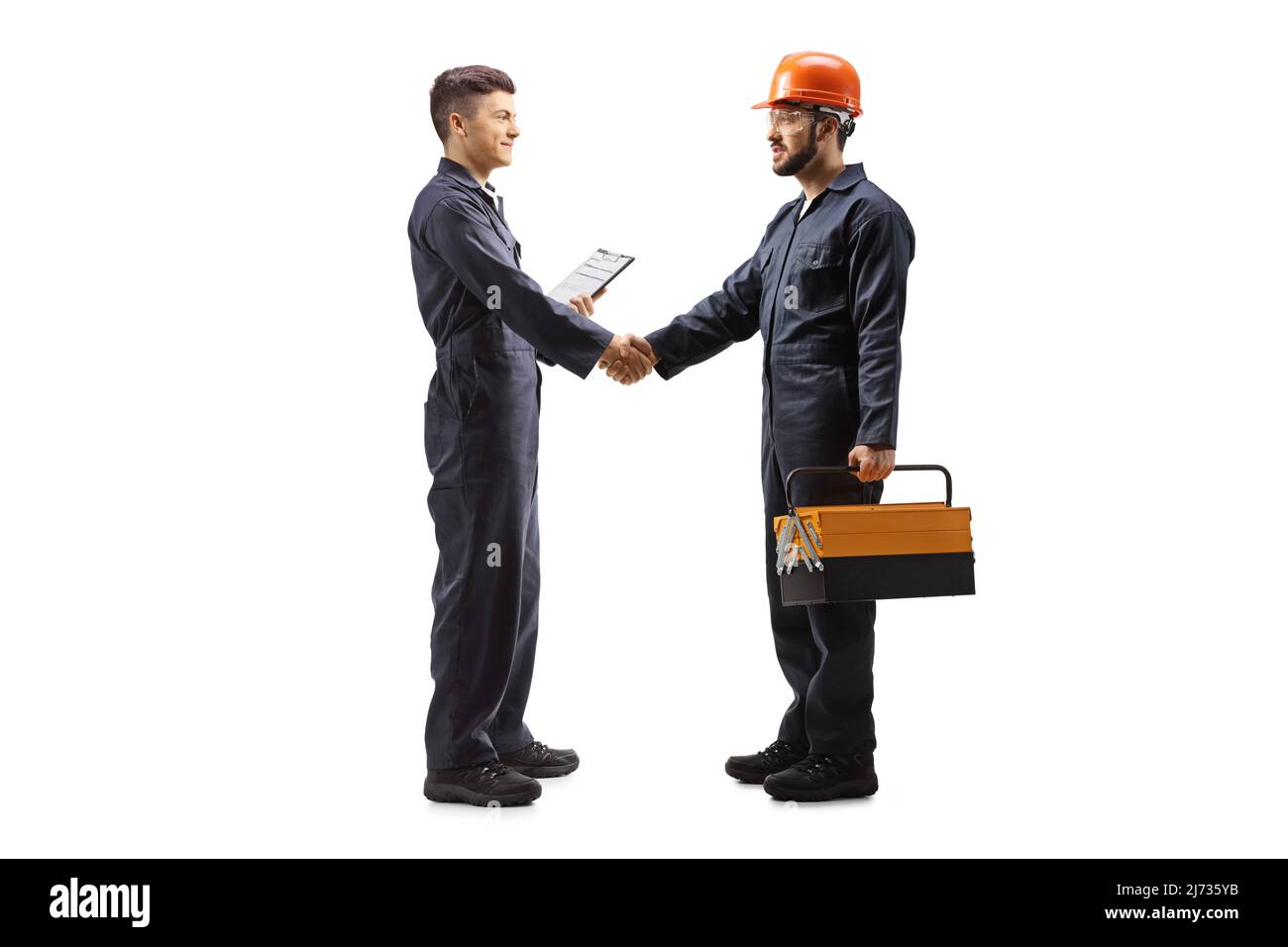 Full length profile shot of factory workers in uniforms shaking hands ...