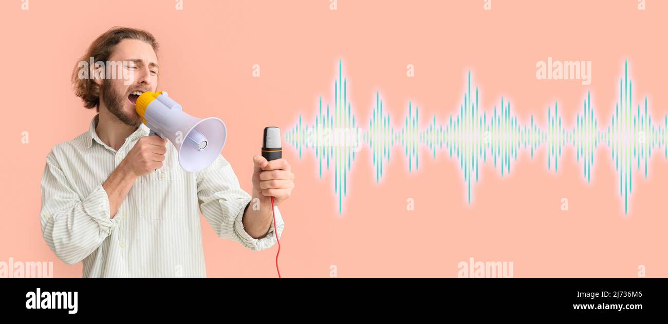Screaming young man with megaphone and modern microphone on pink ...
