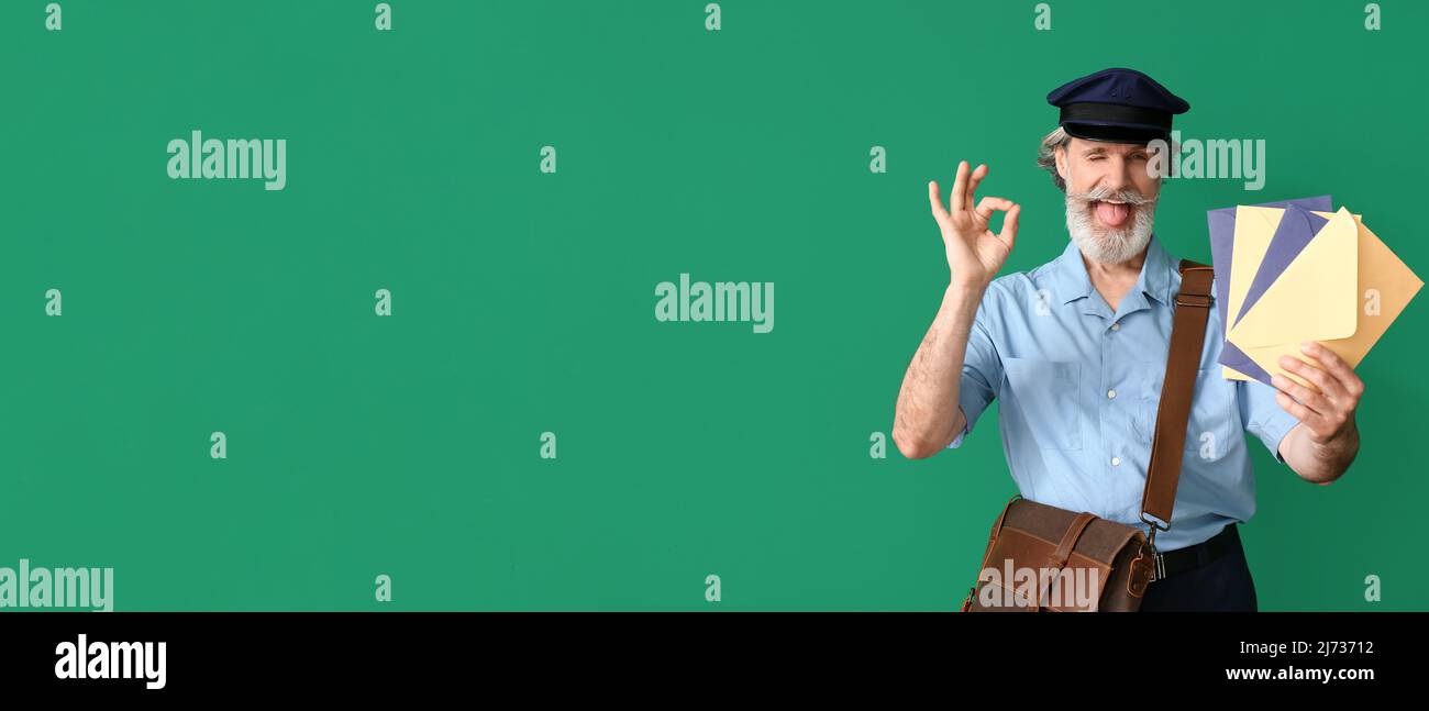 Handsome old postman showing OK on green background with space for text ...