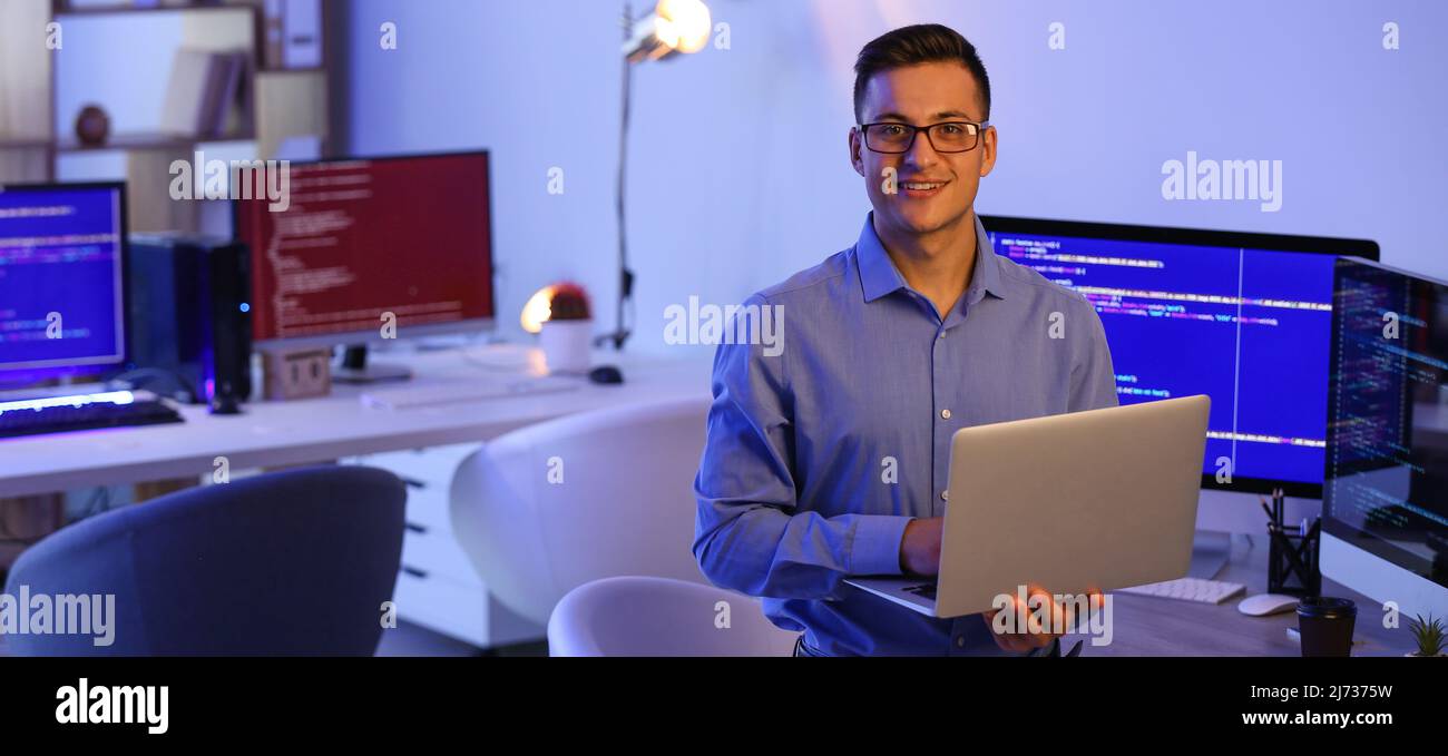 Portrait of handsome programmer with laptop in office Stock Photo - Alamy