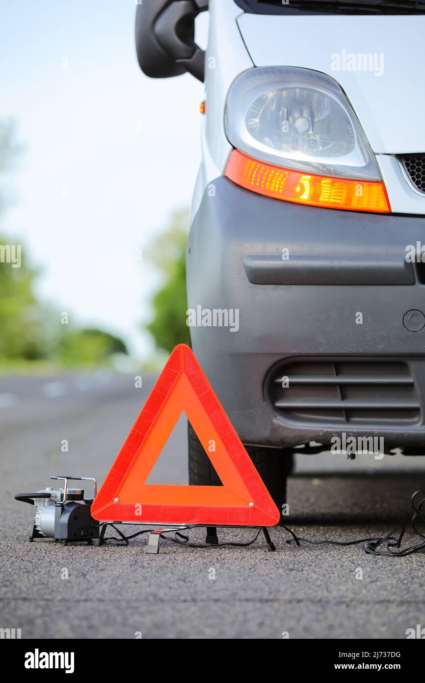 Emergency triangle stop sign and broken car on road Stock Photo - Alamy
