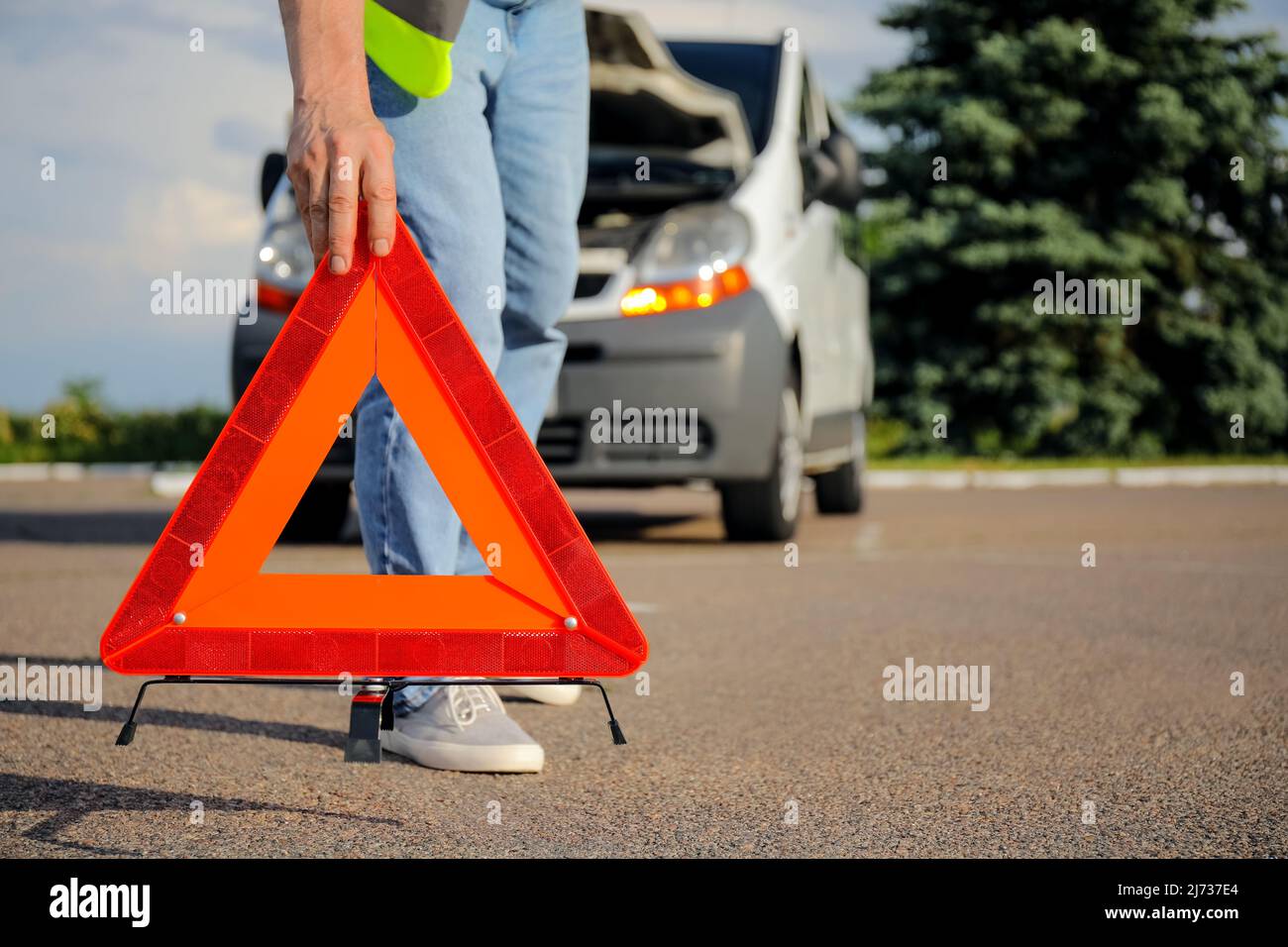 Man putting emergency stop sign near broken car on road Stock Photo - Alamy