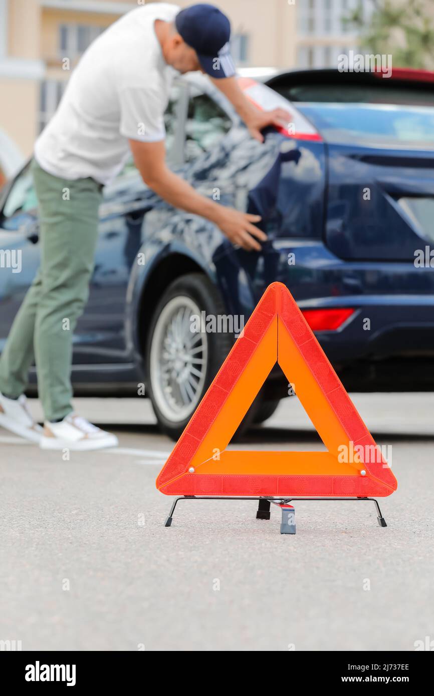 Emergency triangle stop sign and man near broken car outdoors Stock ...