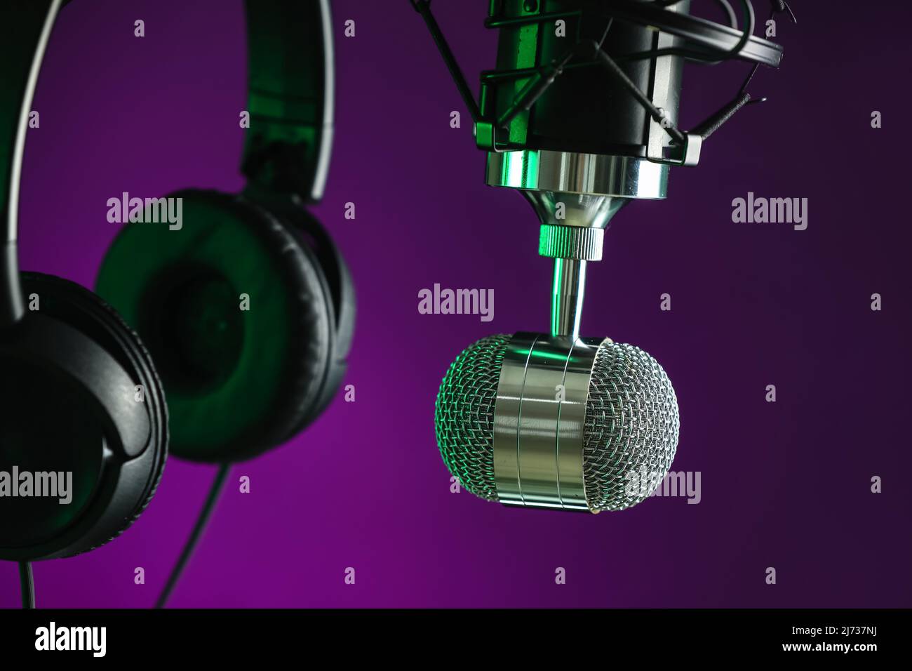 Modern microphone and headphones on dark color background, closeup ...