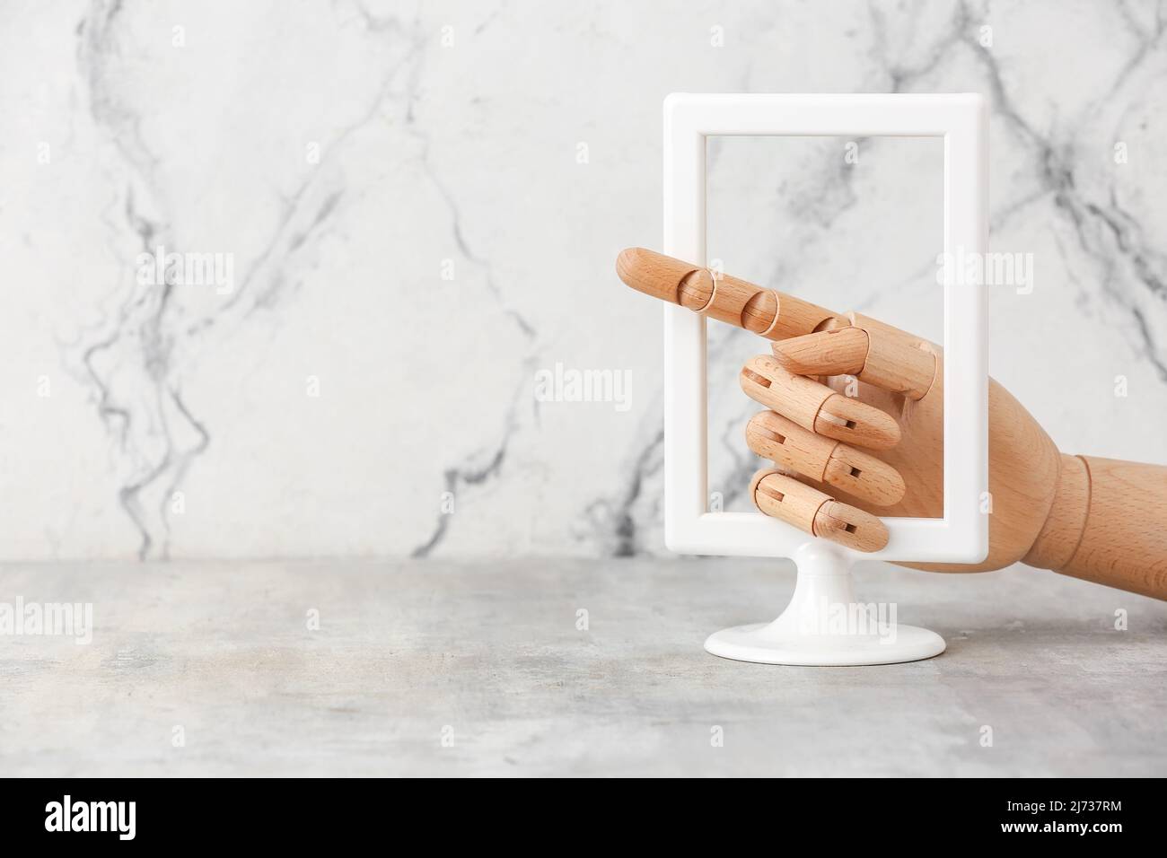 Wooden hand pointing through frame on light background Stock Photo - Alamy