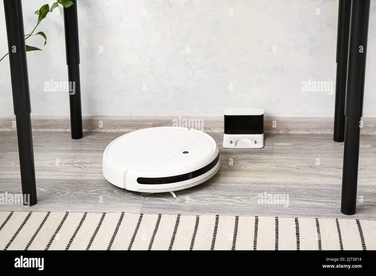 Modern robot vacuum cleaner under table in living room Stock Photo - Alamy