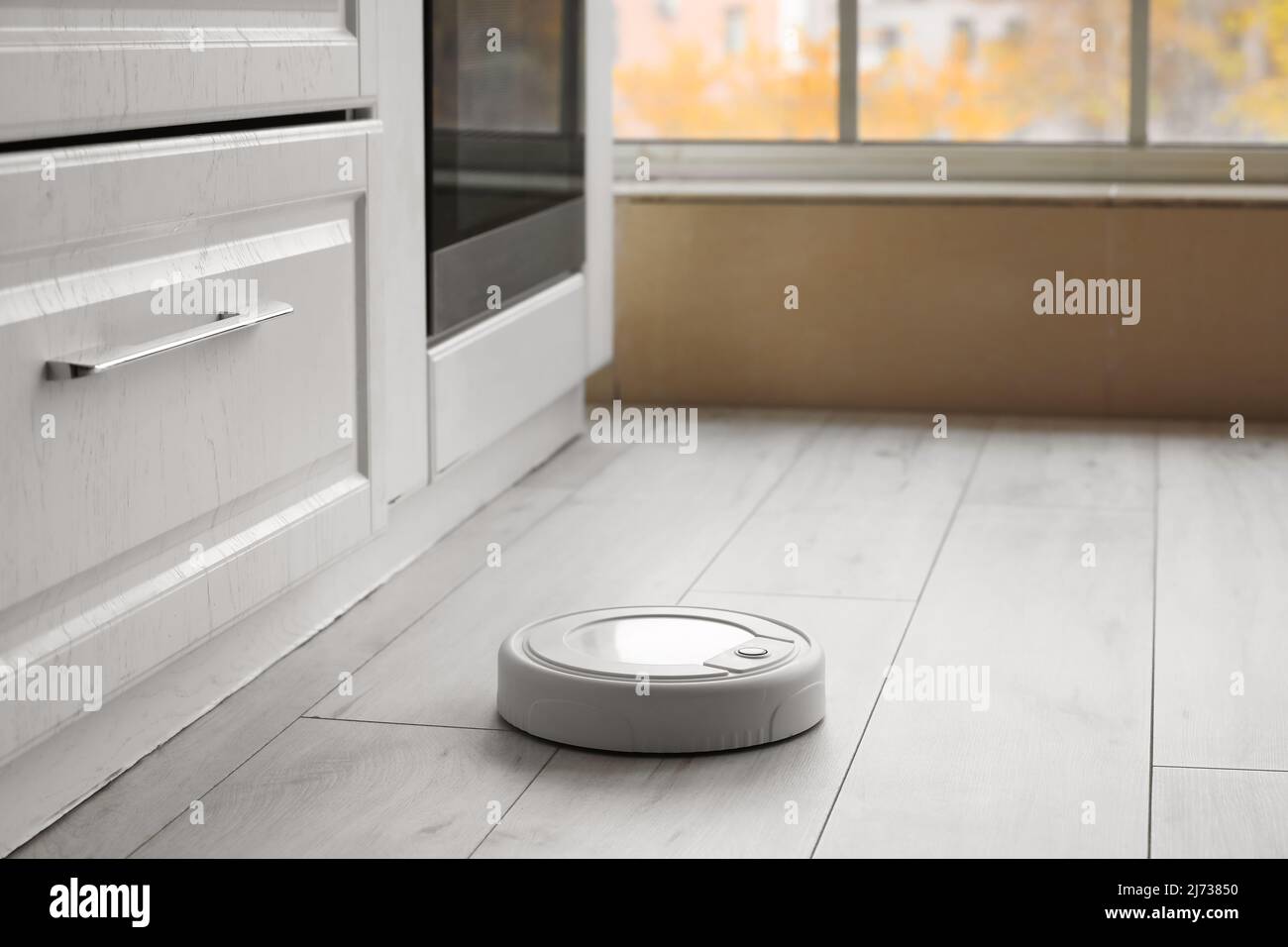 Modern robot vacuum cleaner near counter in kitchen Stock Photo - Alamy