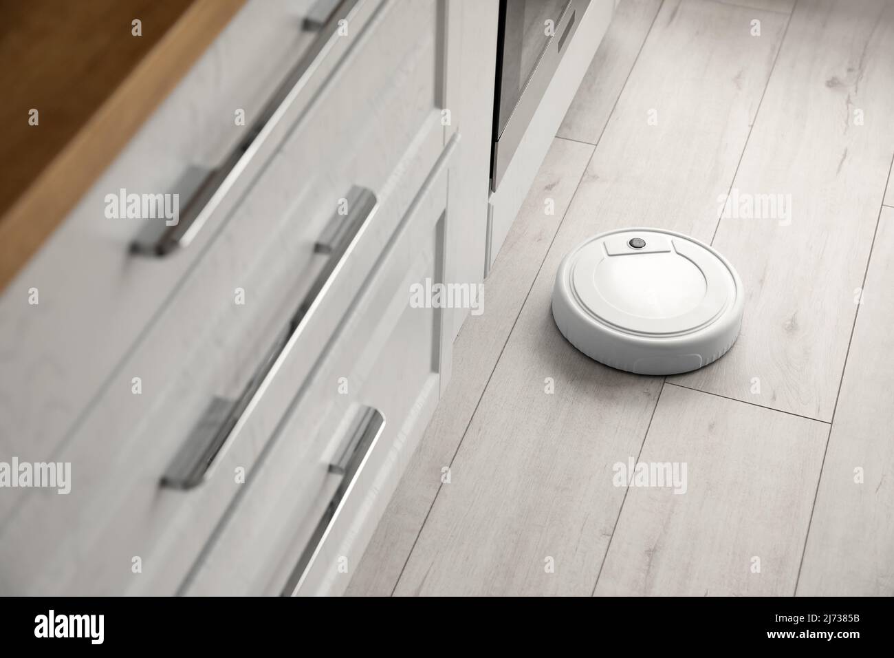 Modern robot vacuum cleaner near counter in kitchen Stock Photo - Alamy