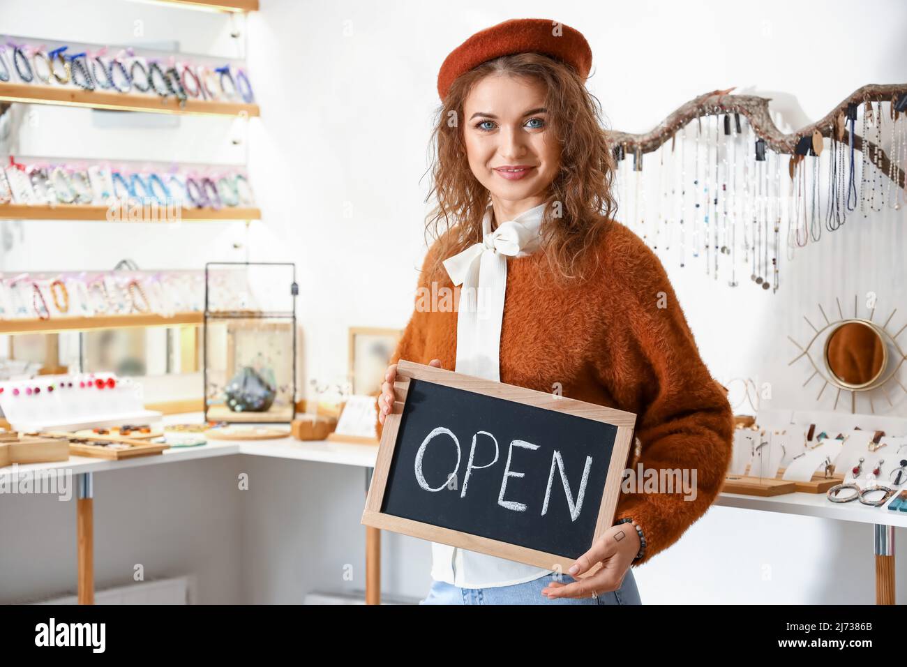 Female business owner holding chalkboard with word OPEN in shop of ...