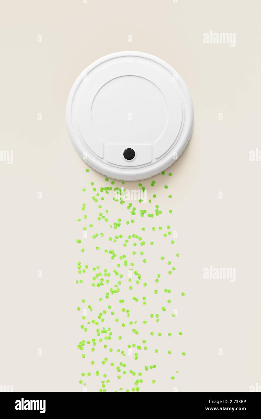 Modern robot vacuum cleaner and green sprinkles on white background ...