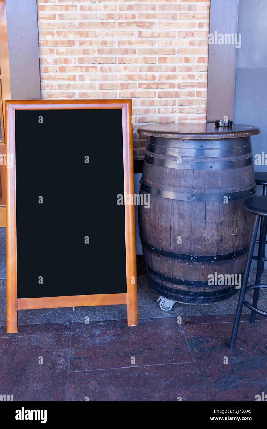 vertical view of a large wooden barrel used as a table and empty black ...