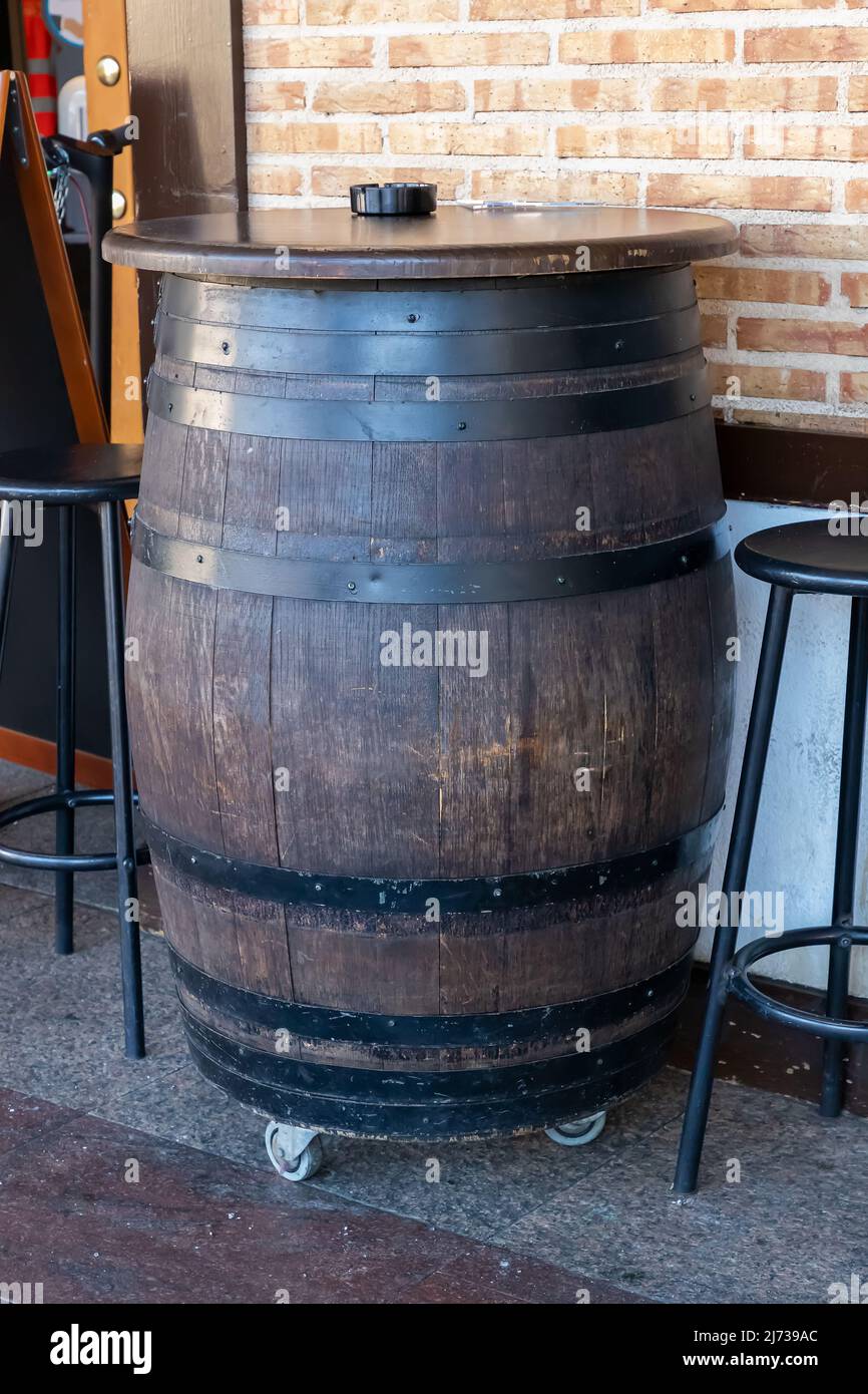 vertical view of a large wooden barrel used as a table on the outside ...