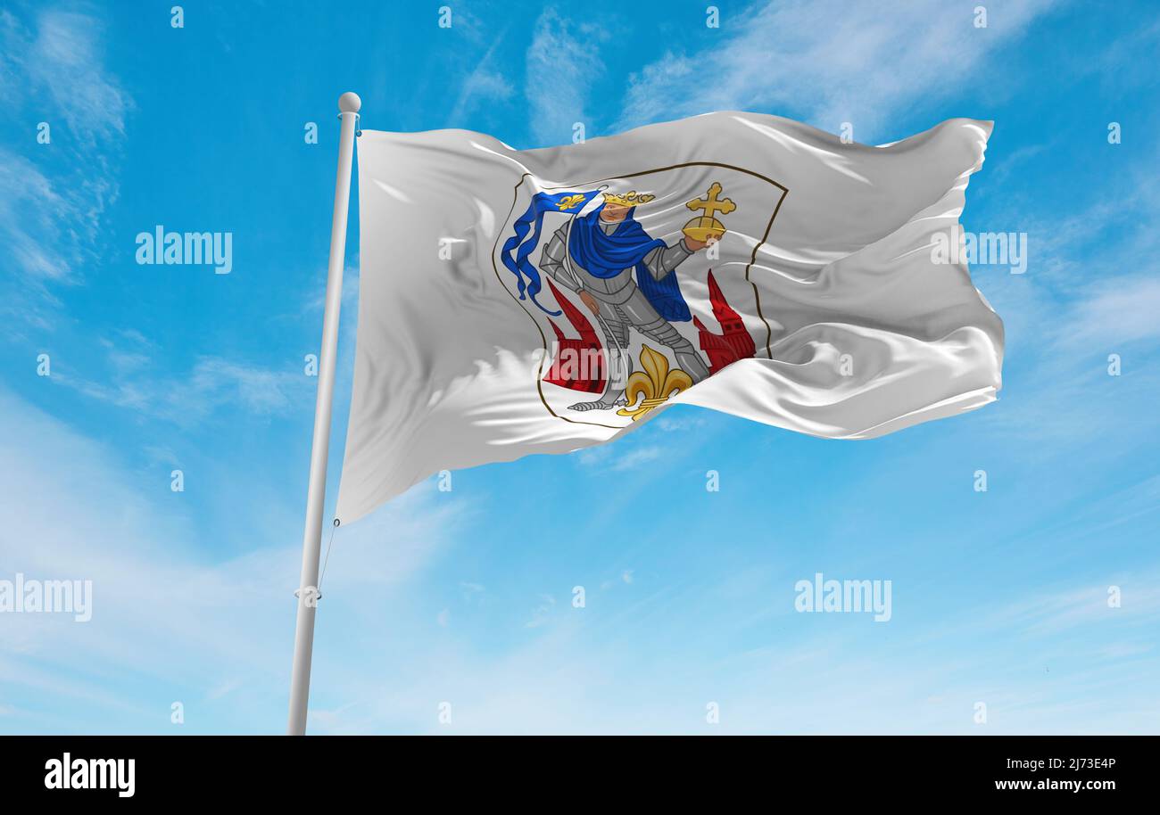 official flag of Odense , Denmark at cloudy sky background on sunset ...