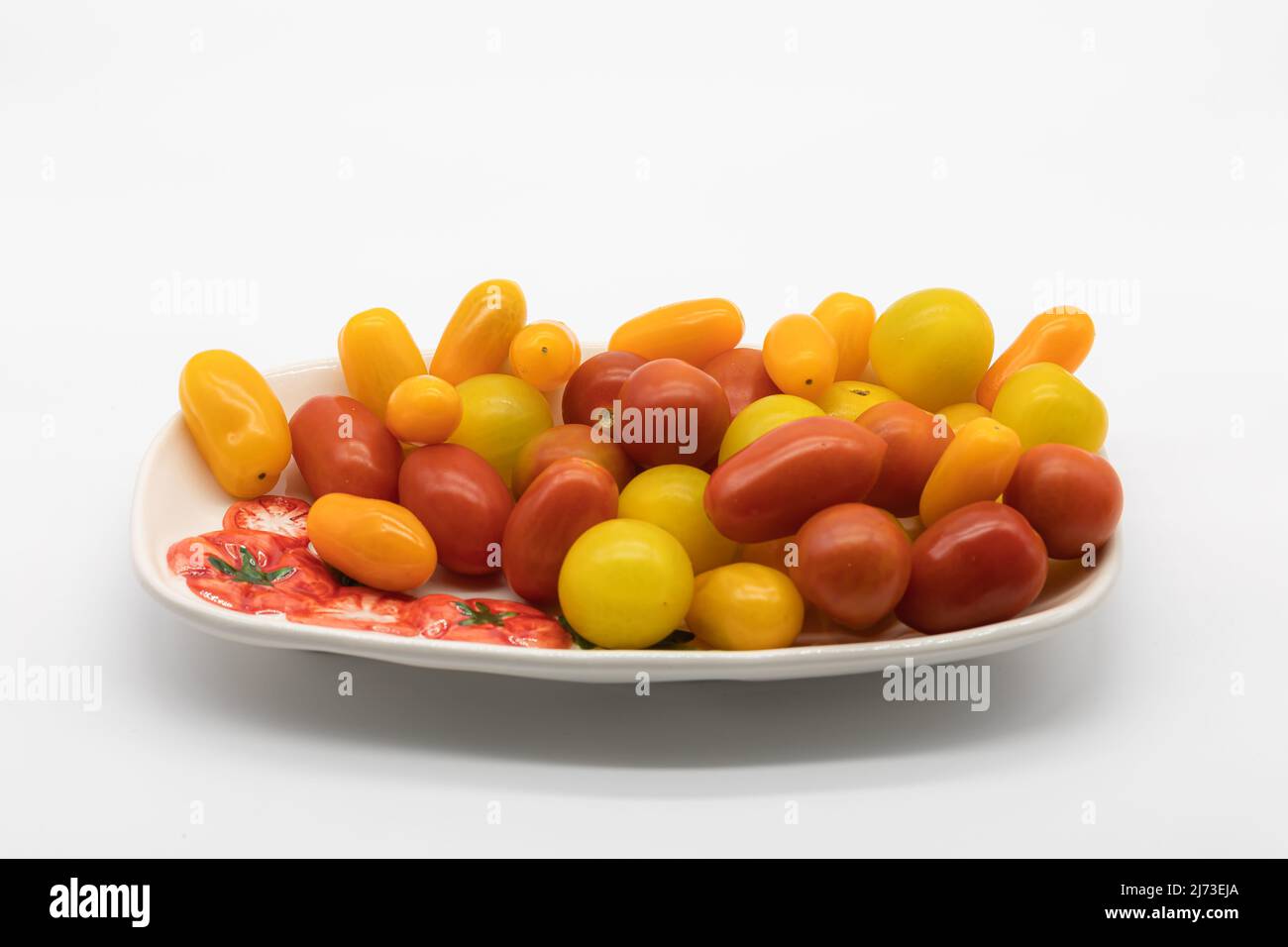 Different types of colorful tomatoes in a font on a white background ...