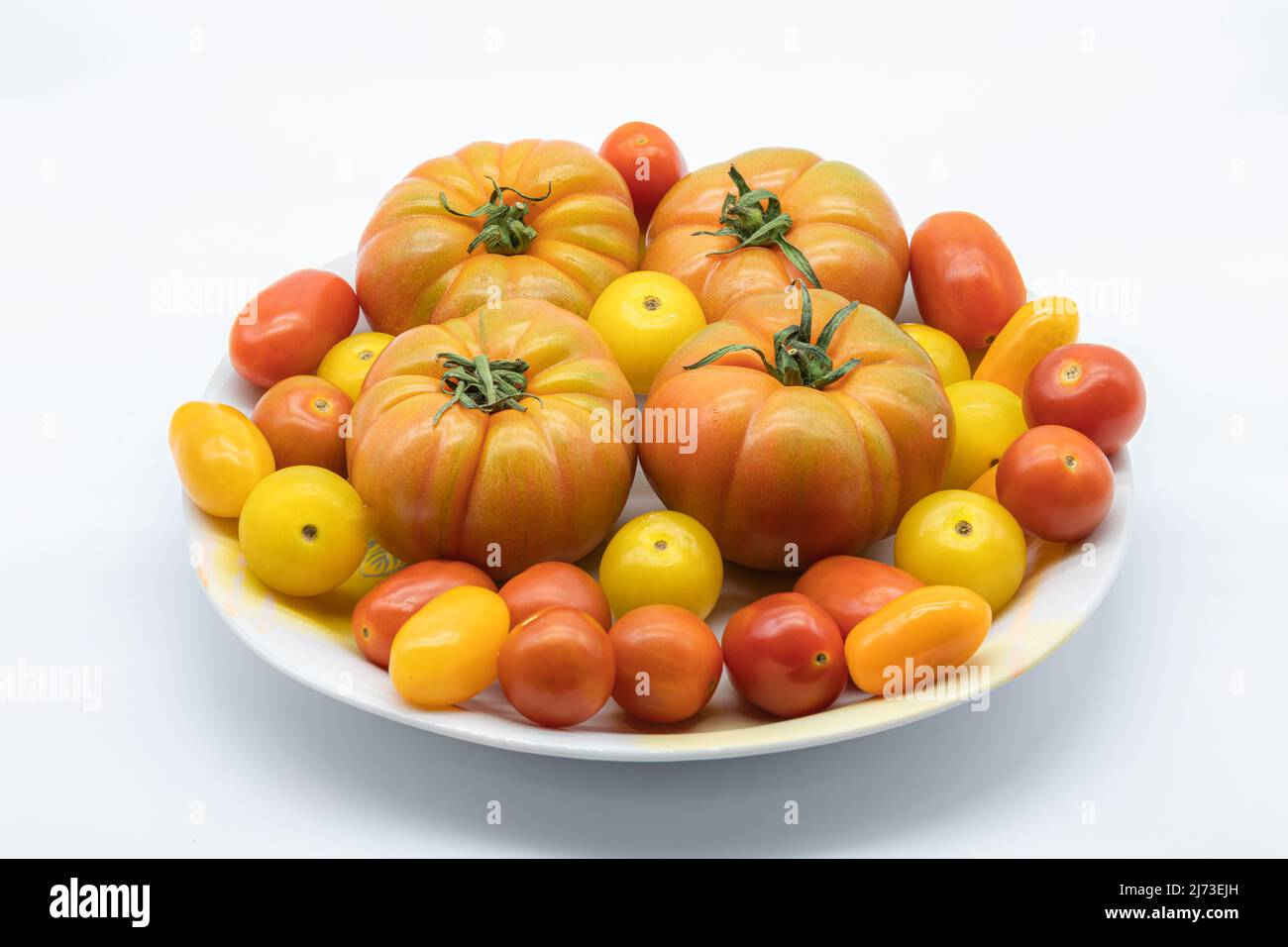 Different types of tomatoes in size and color in a round dish on a ...