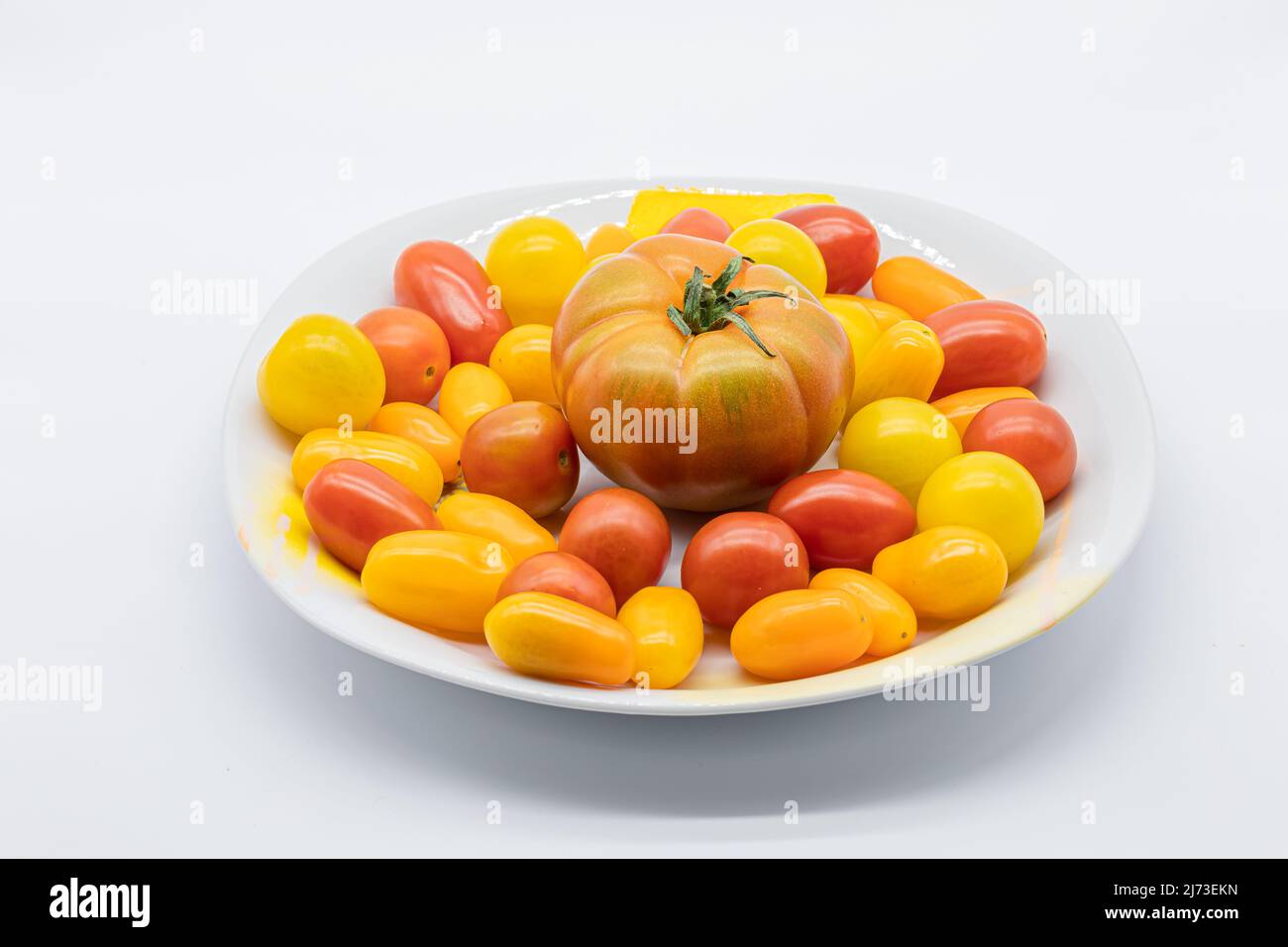 Different types of tomatoes in size and color in a round dish on a ...