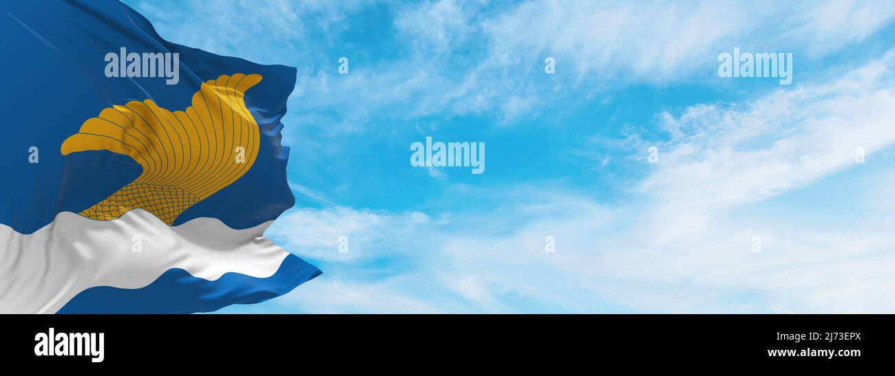 official flag of Vantaa , Finland at cloudy sky background on sunset ...