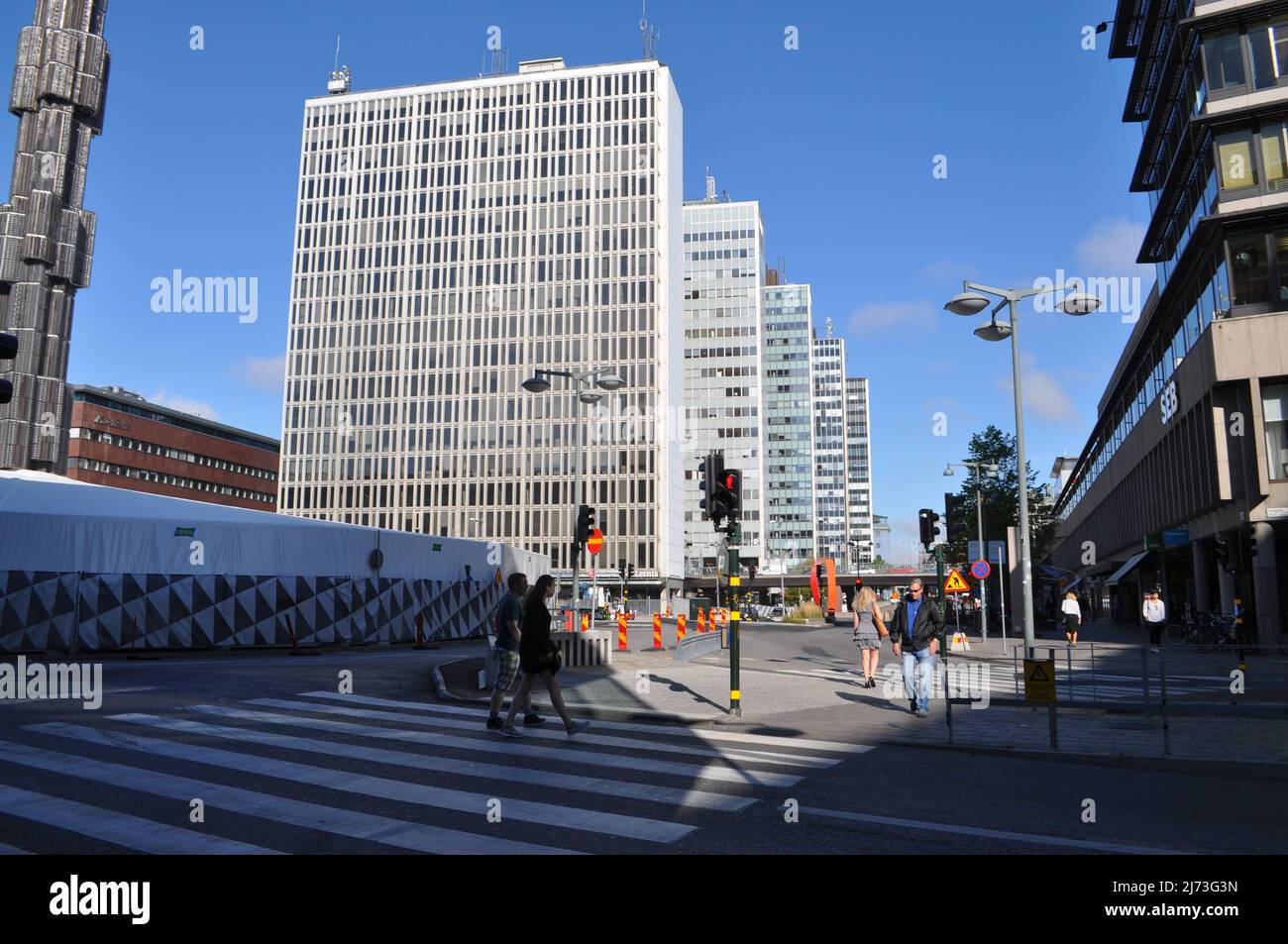 People walking near a crosswalk / pedestrian crossing and modern tower ...