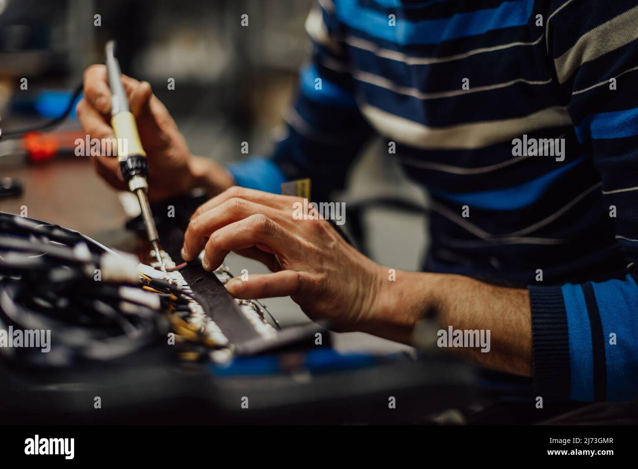 Industrial worker man soldering cables of manufacturing equipment in a ...