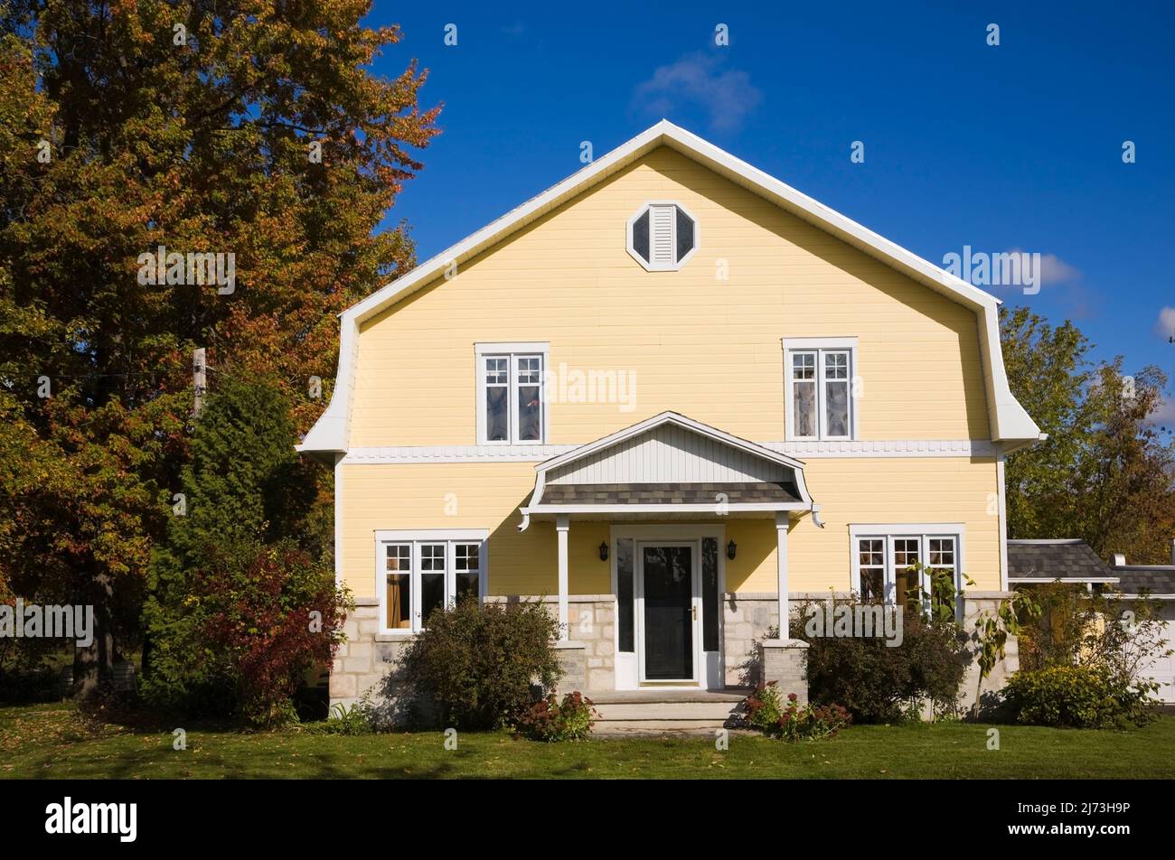 Yellow two story cut stone and wood plank cladded barn style home with ...