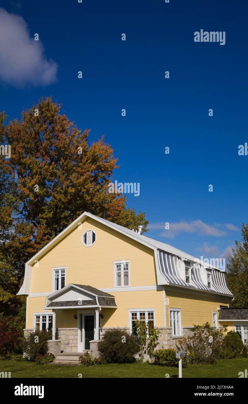 Yellow two story cut stone and wood plank cladded barn style home with ...