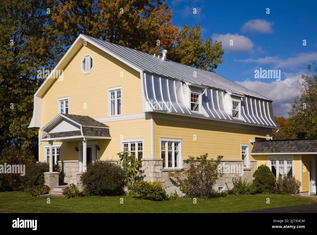 Yellow two story cut stone and wood plank cladded barn style home with ...