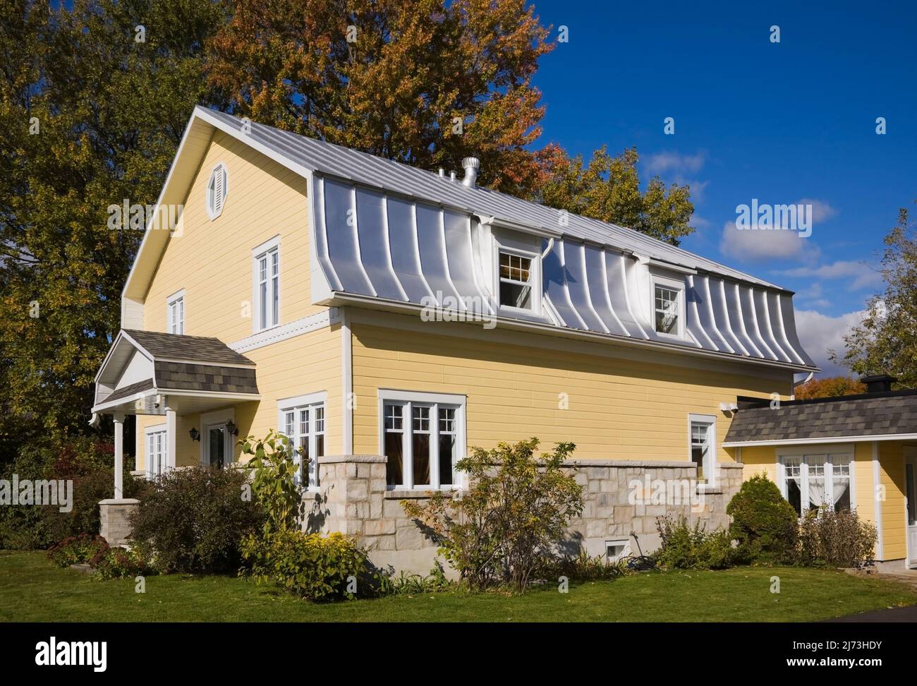 Yellow two story cut stone and wood plank cladded barn style home with ...
