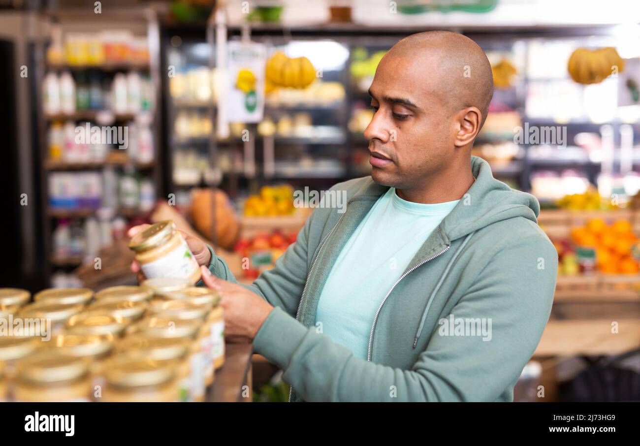 Focused man reading product contents on jar in grocery store Stock ...