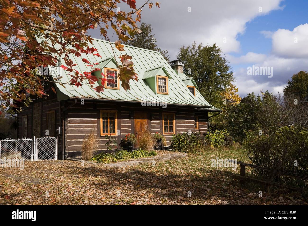 Old 1800s Canadiana style log home with landscaped front yard in autumn ...