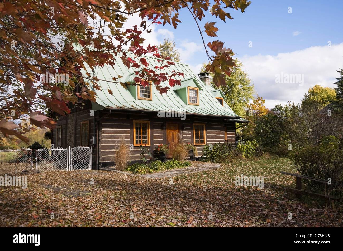 Old 1800s Canadiana style log home with landscaped front yard in autumn ...