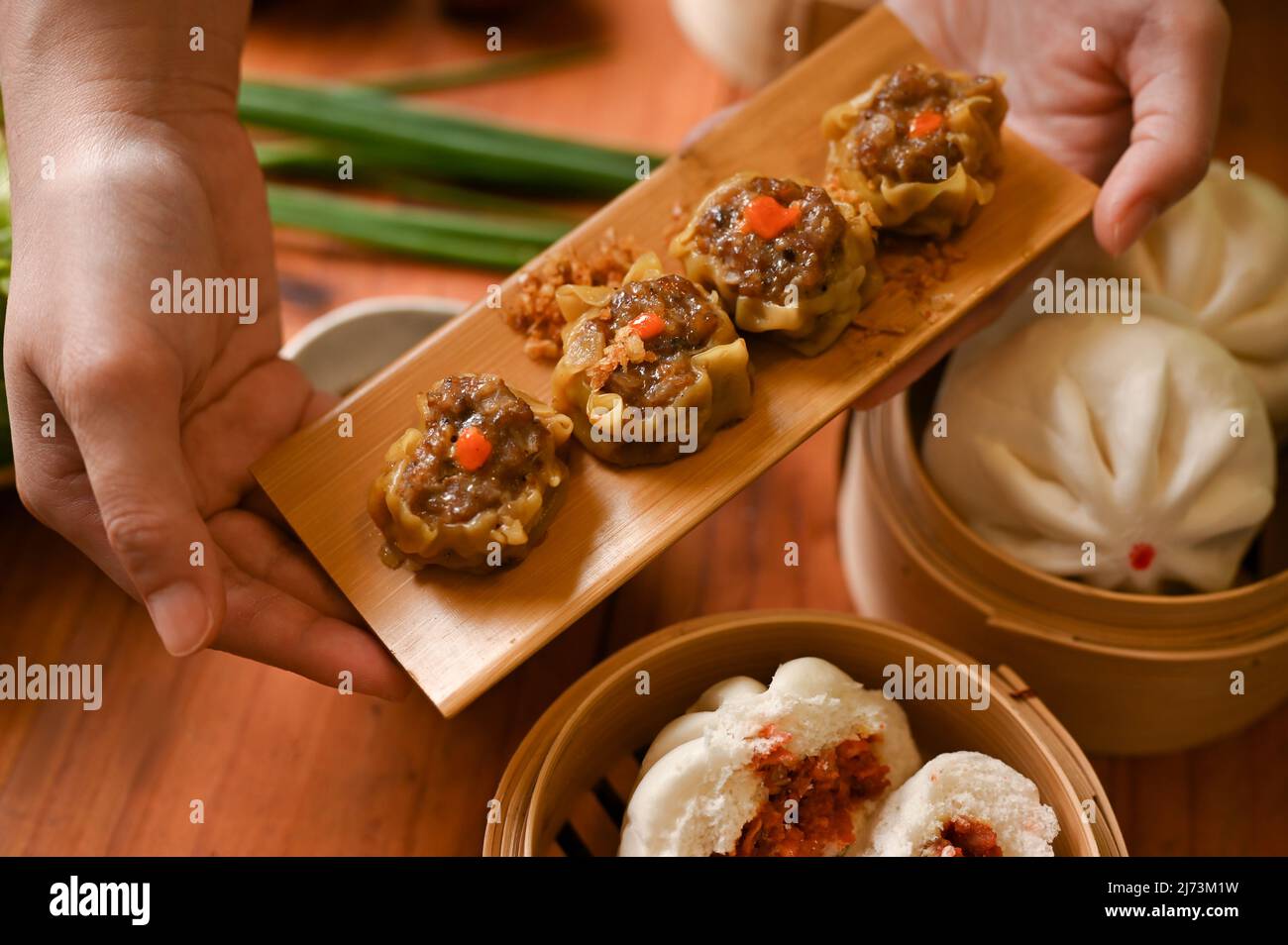 Top view, Female hands serving a plate of tasty steamed pork dumplings ...