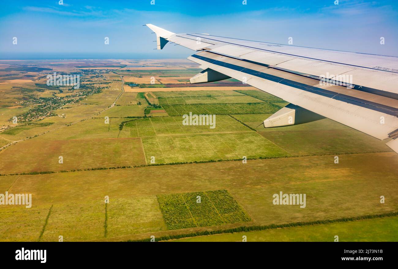 View of airplane wing, blue skies and green land during landing ...