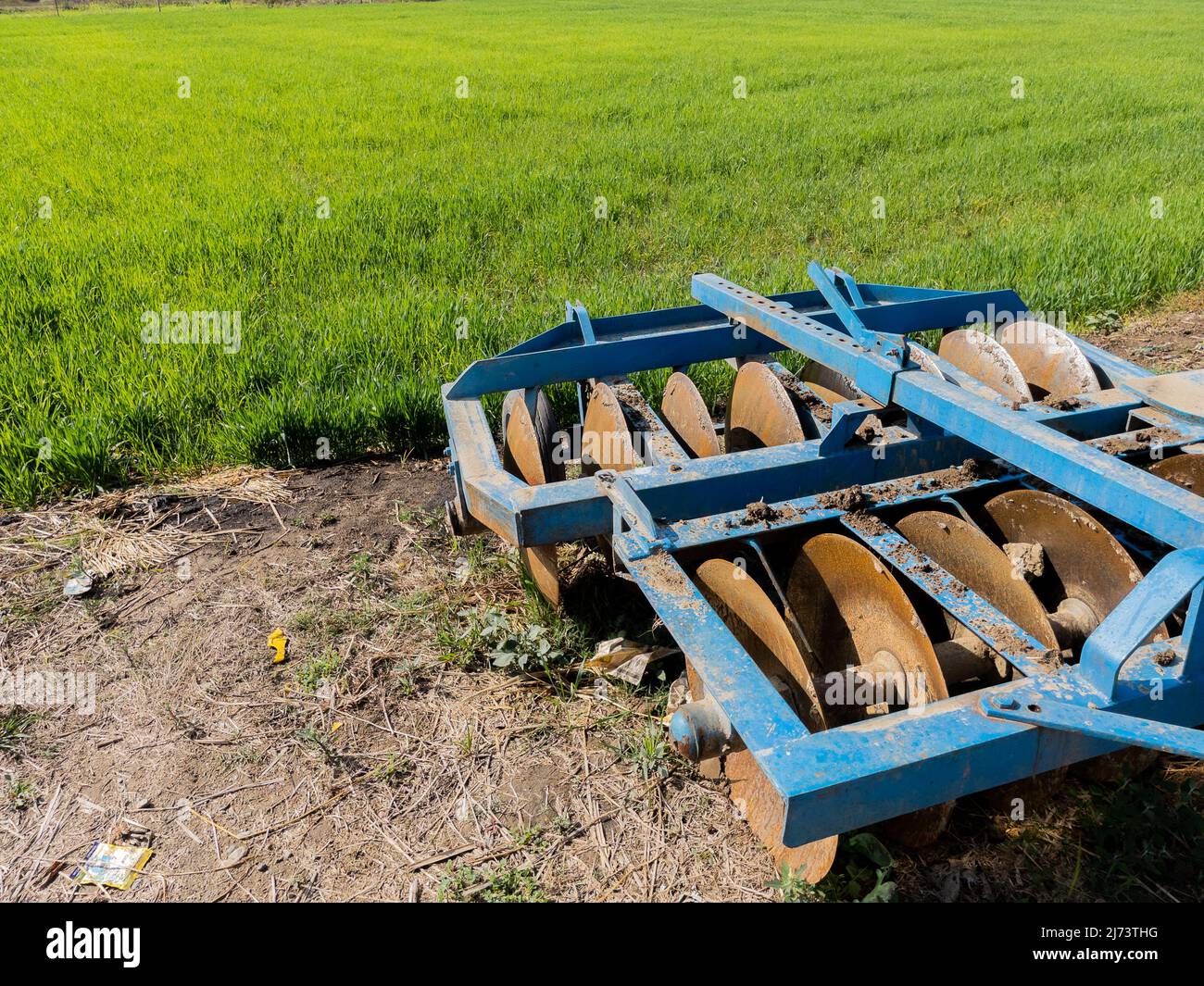An agriculture equipment with harrow blades kept on the ground next to ...