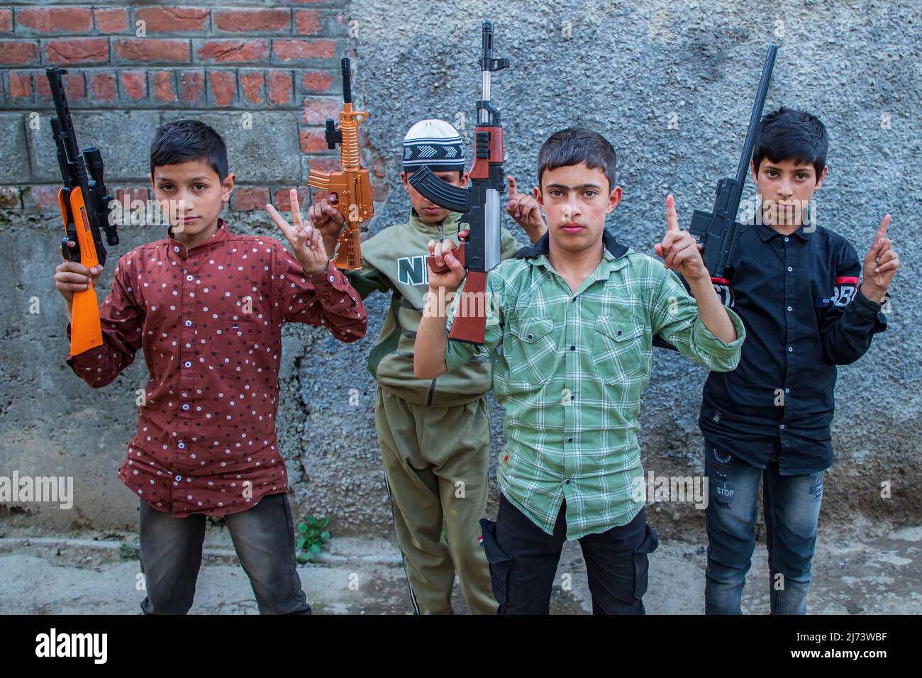A group of Kashmiri Muslim children pose as they play guns. As part of ...