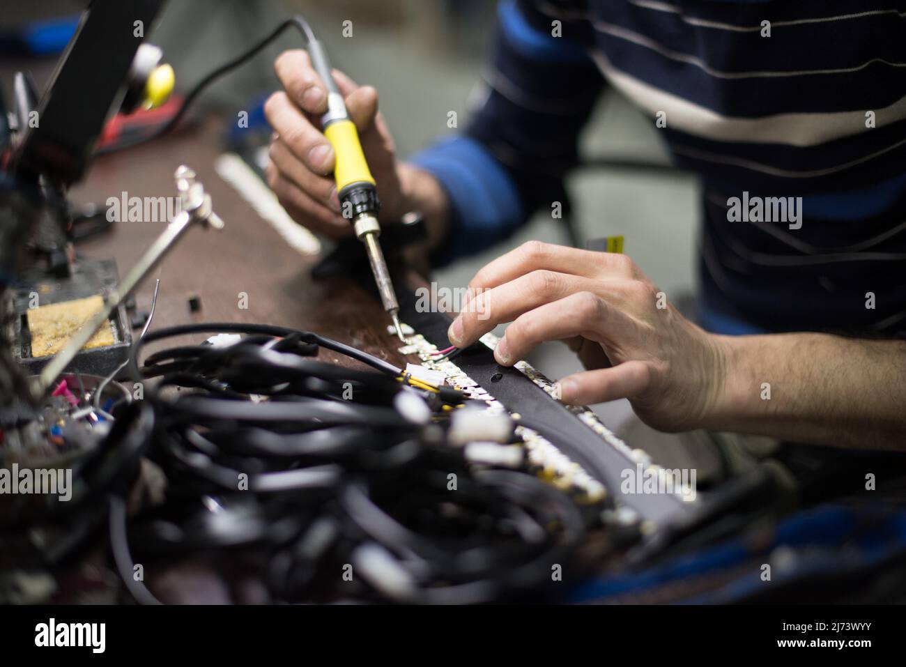 Industrial worker man soldering cables of manufacturing equipment in a ...