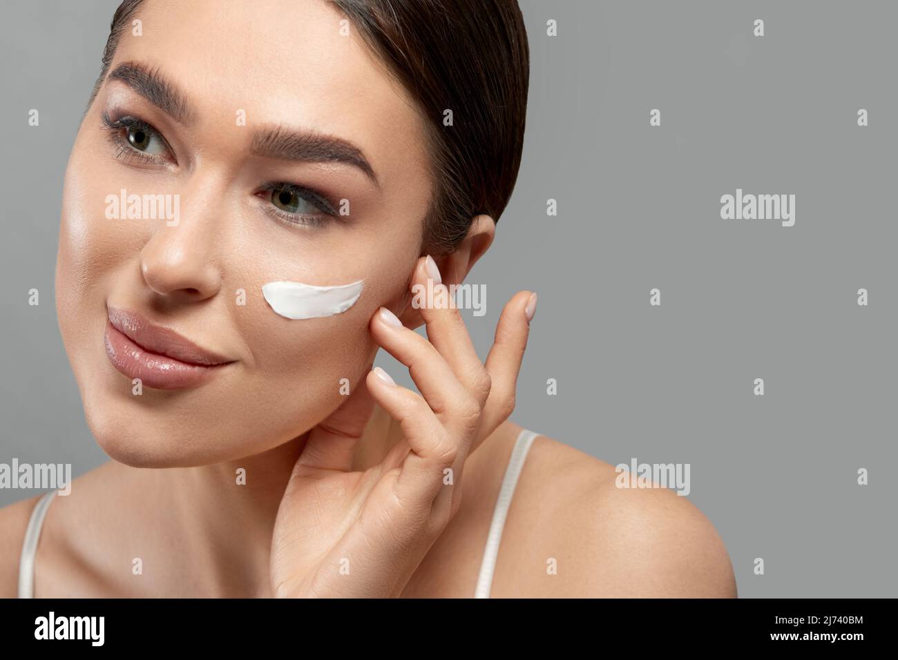 Closeup happy young woman applying cream to her face Skin care and ...