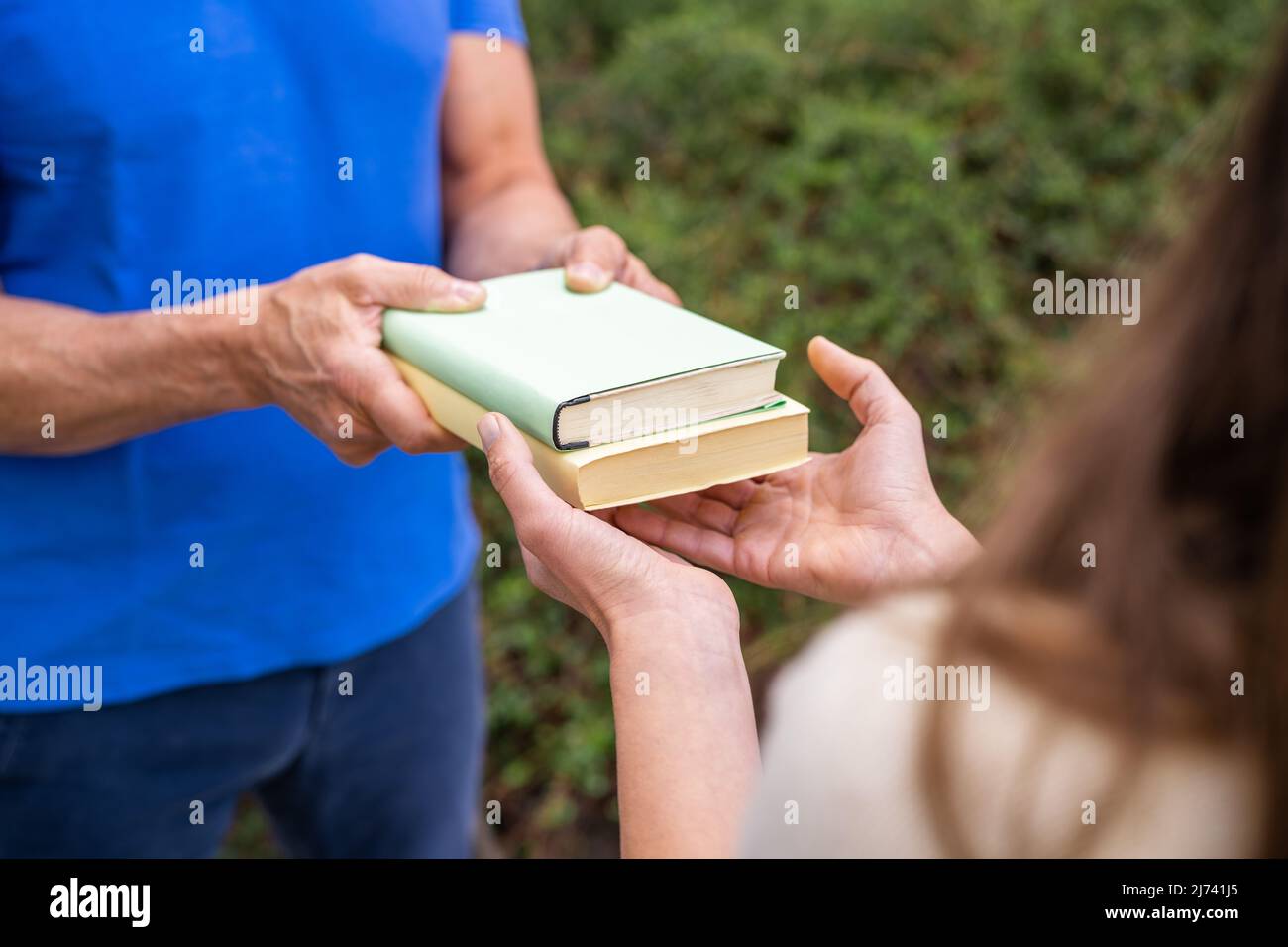 Sharing Books. Hand Closeup Giving Book Outdoors Stock Photo - Alamy
