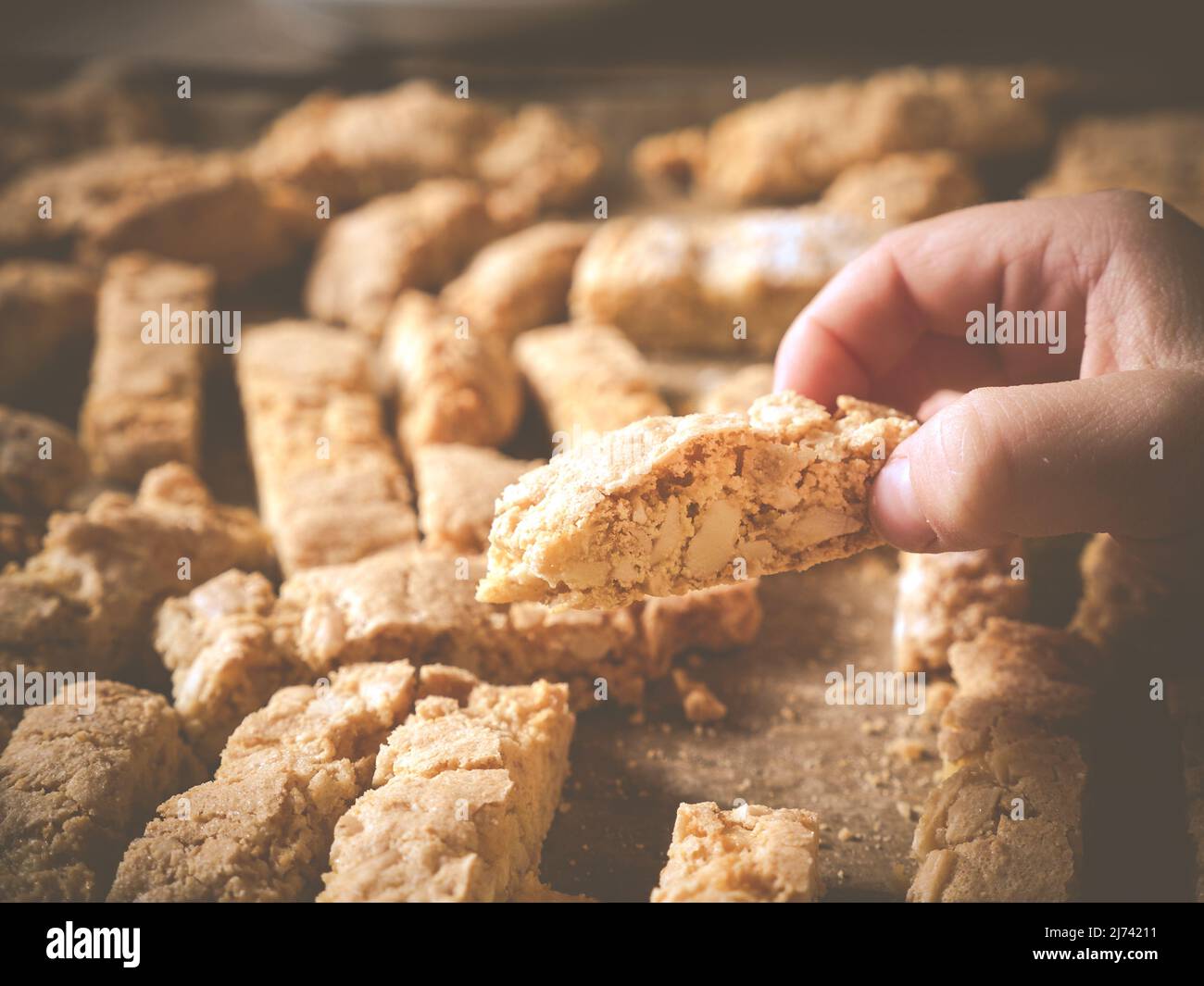 photo shows a jung hand demonstrating a homemade crunchy biscotti; with ...