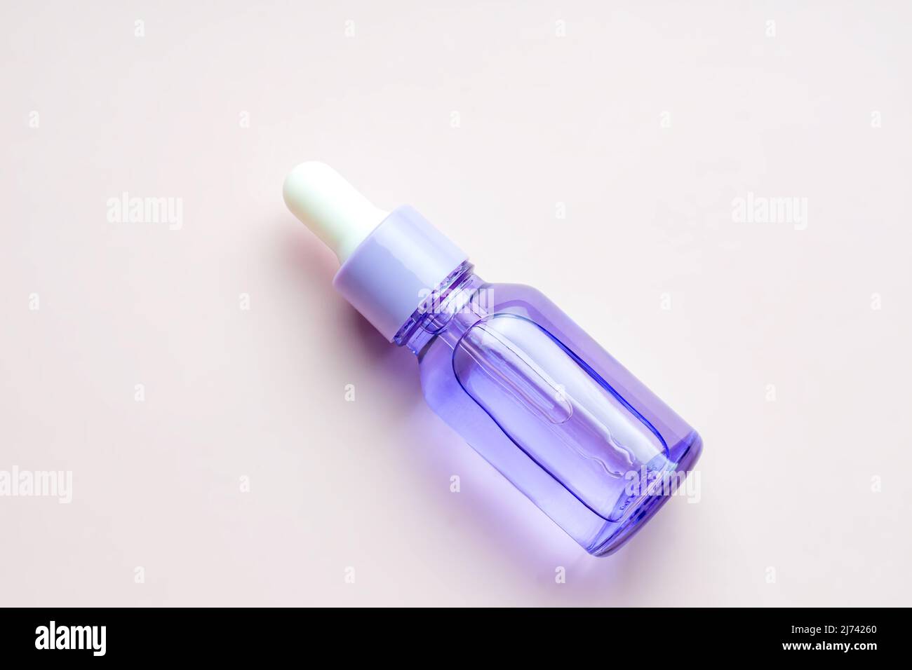 purple dropper bottle with essential oil or face serum on beige ...