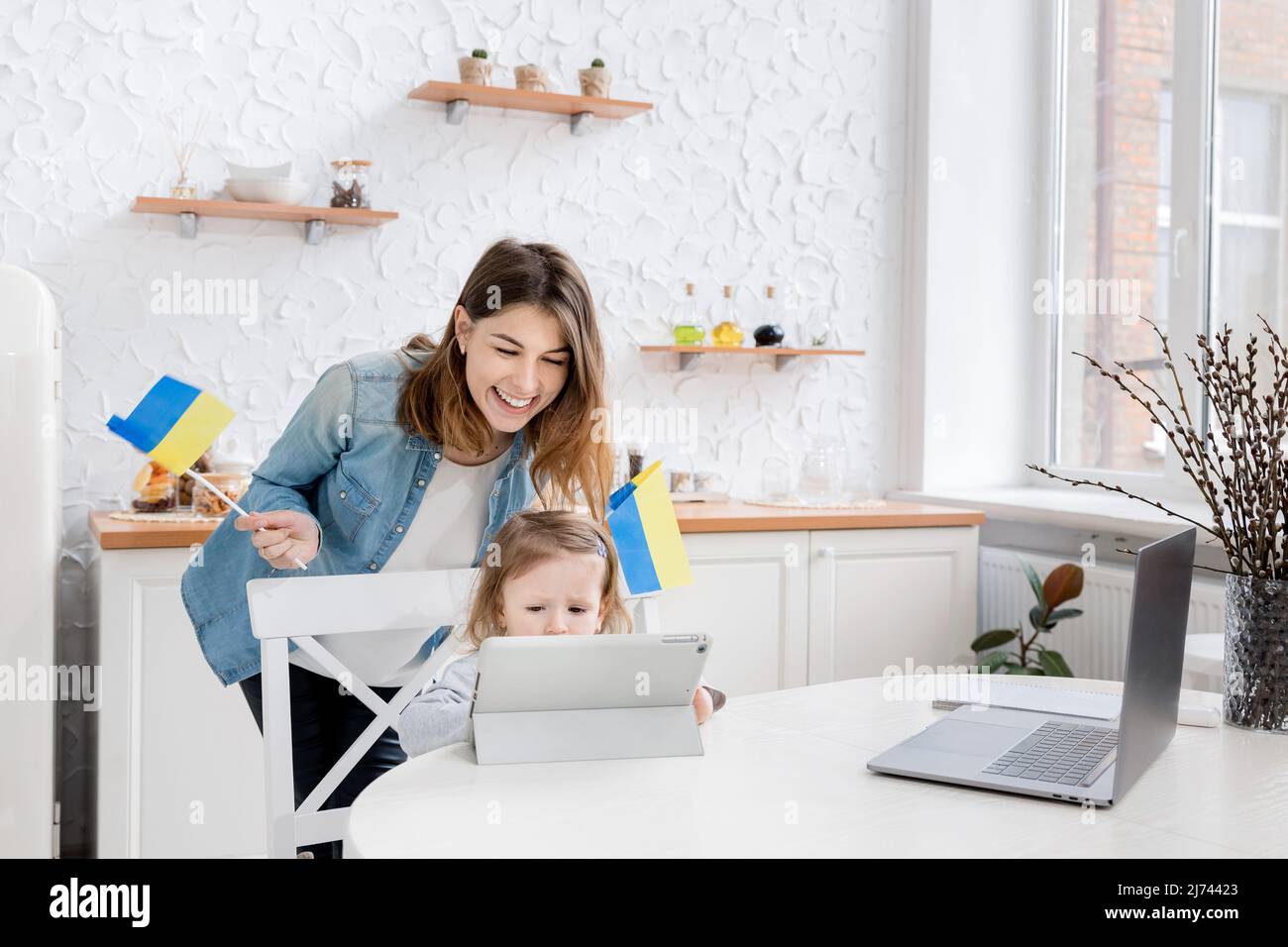 Young smiling mom works at home with her cute baby. Work at home, the ...
