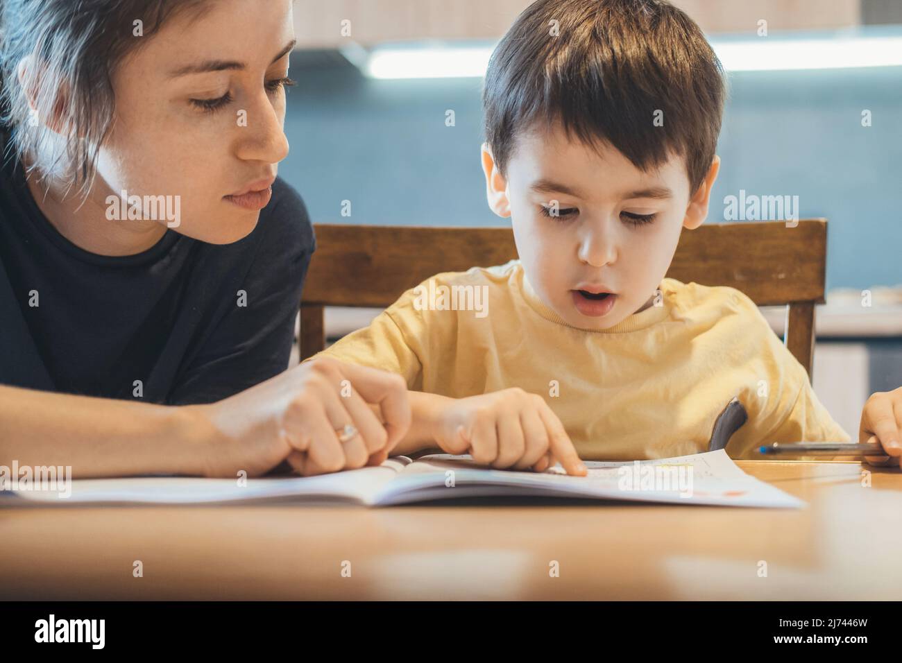 Caucasian little boy and his mother sitting together at table and ...