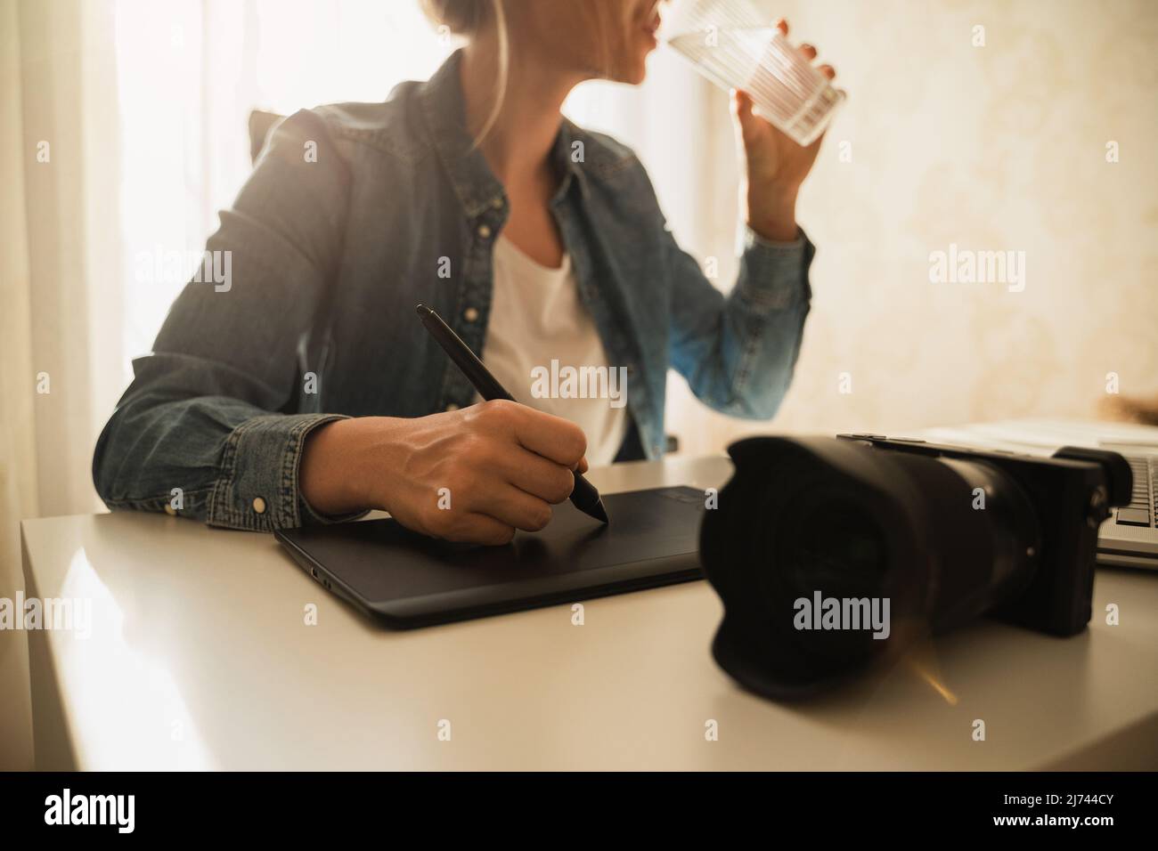 Woman photographer drinking still water on her workplace Stock Photo ...