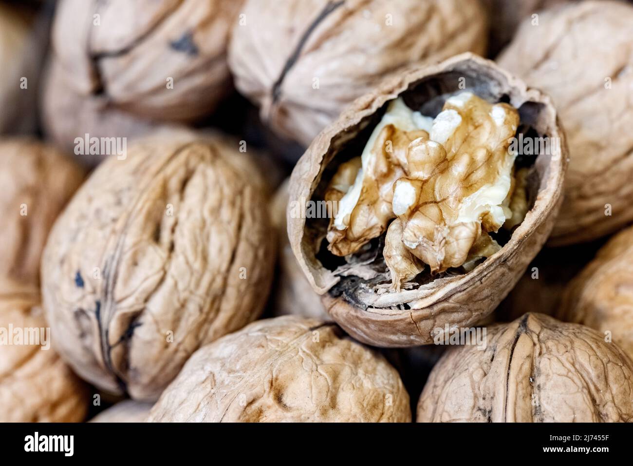 Closeup of split raw walnut on pile of whole walnuts with shells Stock ...
