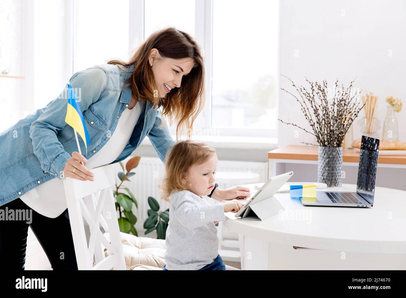 Young smiling mom works at home with her cute baby. Work at home, the ...