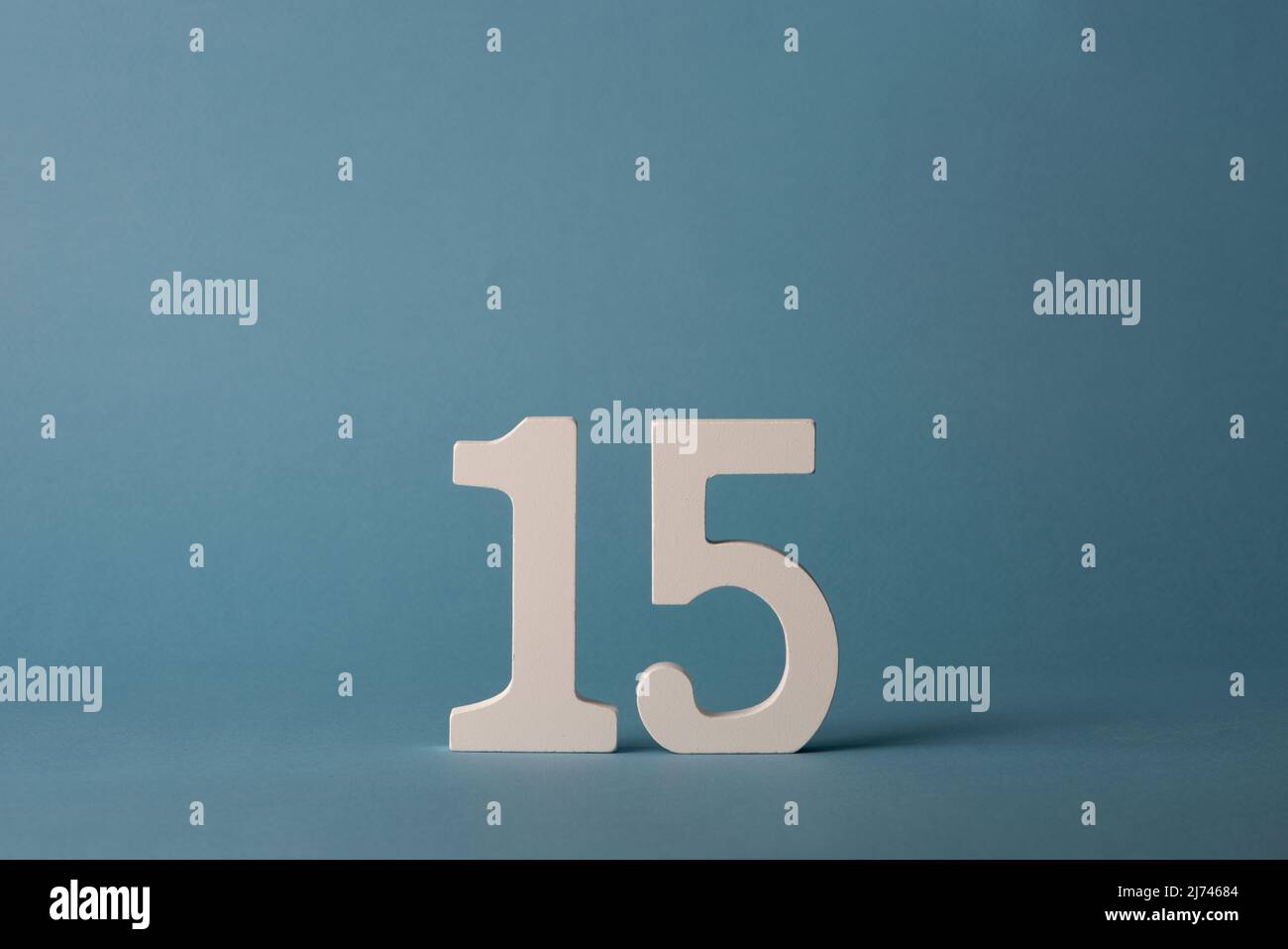 White wooden number fifteen 15 on blue background Stock Photo - Alamy