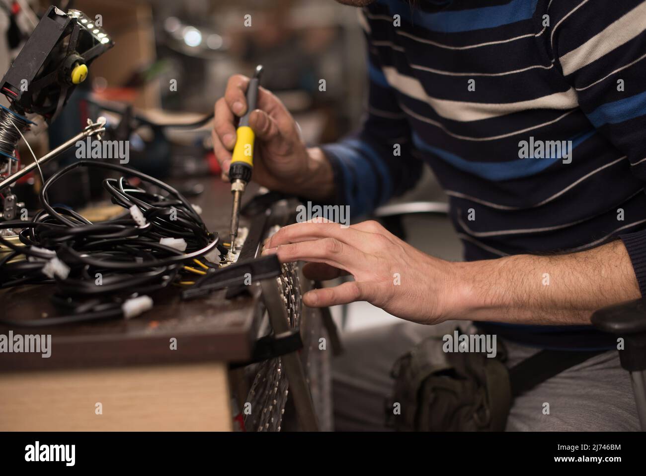 Industrial worker man soldering cables of manufacturing equipment in a ...